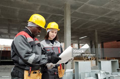 하드 햇과 작업복을 입은 두 명의 심각한 인종 간 엔지니어가 계획을 세우고 있습니다 2명에 대한 스톡 사진 및 기타 이미지 2명 30 34세 50 54세 Istock