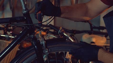 테마 중소 기업 자전거 수리 보호 안경 장갑과 Fartuhe에 젊은 갈색 머리 백인 남자는 수리 및 차고 작업장에서 림 브레이크와 바퀴 회전 자전거를 튜닝하기 위해 손