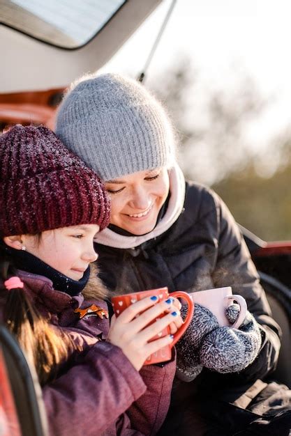 가족 휴가 가족 가치 엄마는 공원에서 겨울에 딸과 즐거운 시간을 보낸다 엄마와 딸은 Suv의 열린 트렁크에 앉아 차를 마시고