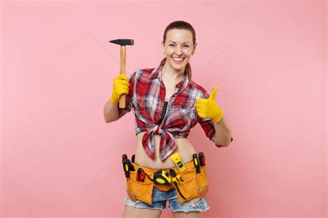 身穿格子衬衫牛仔短裤装满不同乐器锤的工具包的强壮的年轻勤杂工女人在粉红色背景上被隔离男工作中的女装高清图片下载 正版图片504625152 摄图网