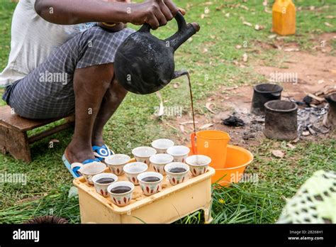 Woman Pouring Traditionally Brewed Coffee Into Finjal Coffee Cup From A Jebena Coffee Pot