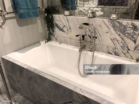 흰색 회색 대리석 벽과 바닥 타일 흰색 세라믹 욕조 싱크대 화장실 스테인레스 스틸 빅토리아 믹서 탭 및 샤워 배관 인공 후행 식물 거울 수건 레일 타일 바닥 바닥이있는 고급