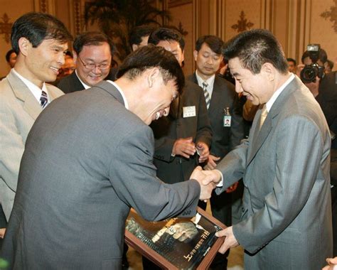 [노무현사료관] [유시민 열린우리당 국회의원 당선자로부터 탄핵관련 패러디 포스터 설명들으며 미소짓는 노무현 대통령]