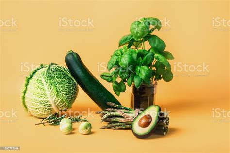 양배추 호박 아스파라거스 브뤼셀 콩나물 아보카도 오렌지 배경에 바질의 신선한 야채와 추상 구성 채식주의 자 및 비건 식단 지속