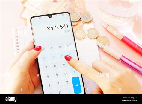 Girl Calculating With Smartphone And Coins In The Background Stock
