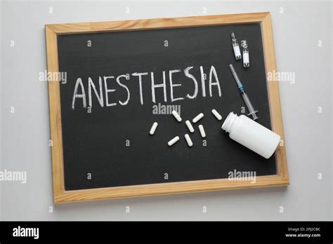 Blackboard With Word Anesthesia Syringe And Drugs On Light Grey Background Top View Stock