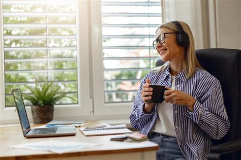 La programadora con auriculares disfruta del café mientras trabaja desde el concepto de trabajo ...