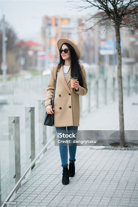 가을 도시 거리에서 코트와 모자를 쓰고 술을 마시는 젊은 여성이 종이 컵에 커피를 가져 가라 이동 중에 아침 식사 가을에 대한 스톡 사진 및 기타 이미지 Istock