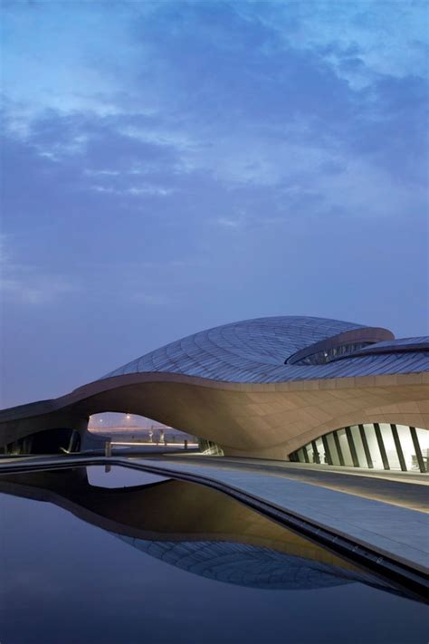 A Large Building That Is Next To A Body Of Water In The Evening Time With Blue Sky And Clouds