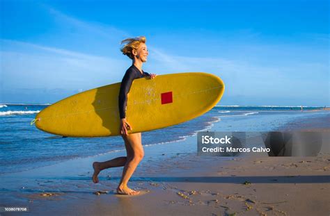 매력적이 고 행복 한 젊은 금발 서퍼 여자 서핑 라이프 스타일 개념에 있는 열 대 섬에 여름 휴가 즐기고 바다 실행 노란 서핑 보드를 들고 아름 다운 해변에서 여자 건강한