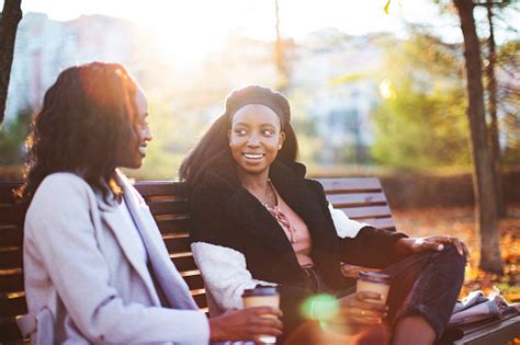 두 명의 젊은 흑인 여성 친구가 공원 벤치에 앉아 커피를 마시며 이야기를 나눴다 10월에 대한 스톡 사진 및 기타 이미지 10월 20 24세 2명 Istock