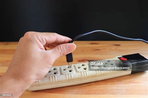 손 들고 전기 플러그 나무 배경과 검은 벽에 전기 세 눈 플러그 케이블에 대한 스톡 사진 및 기타 이미지 케이블 손 여자