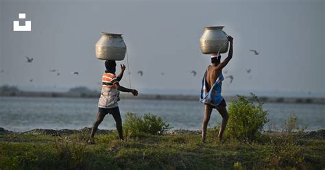 A Couple Of People Carrying Buckets On Their Heads Photo Free 4k
