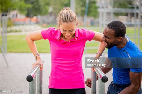 아프리카 계 미국인 피트니스 강사 코칭은 공원의 수평 바 스테이션에 교차 맞춤 수평 바 스테이션에서 푸시 업을하는 여성을