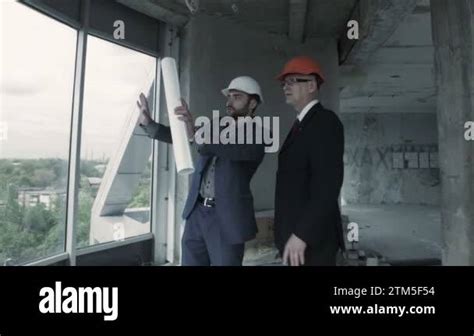 two men in suit and helmet discuss blueprint calculate and communicate