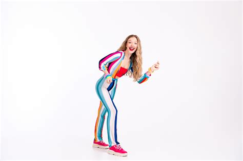 화려한 줄무늬 의상을 입은 젊은 여성이 밝은 흰색 배경에 활기찬 패션과 라이프 스타일을 선보이며 활기차게 포즈를 취하고 있습니다 16 17 살에 대한 스톡 사진 및 기타