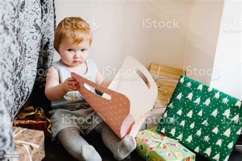 방에 있는 작은 소녀의 초상화 앉아서 선물 압축을 풉니다 축제 생일 개념입니다 사진에서 행복 한 아기입니다 유아입니다 국제 여성의 날 3 월의 8 번째입니다 메리 크리스마스