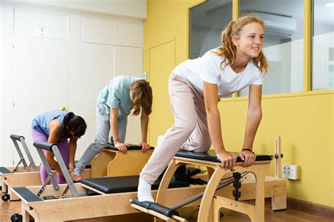 피트니스 스튜디오에서 개혁가에 대한 필라테스 운동을 수행하는 어린 소년과 소녀 12 13세에 대한 스톡 사진 및 기타 이미지 12 13세 14 15 살 3 명