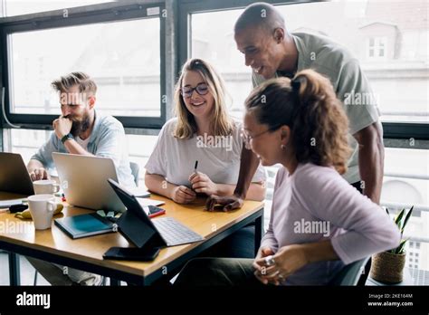 Happy Female And Male Computer Programmers Planning Strategy Over Laptop In Startup Company