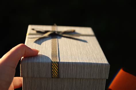 최소한의 검은 색 배경에 리본 리본으로 감싸인 빈티지 선물 상자를 들고 있는 여성 핸드 상자를 제시합니다 휴일 개념 축제 배경 코너의 플레어 개념에 대한 스톡 사진 및 기타