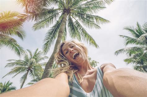 휴가 재미에 야자수 아래 Selfie를 복용 하는 젊은 여자 즐기는 열 대 기후 백인 여성 이국적인 목적지에 자기 초상화를 캡처 야자 나무 Arecales에 대한 스톡