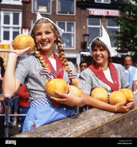 Two Dutch Girls In Traditional Dress Selling Cheeses At Alkmaar Stock