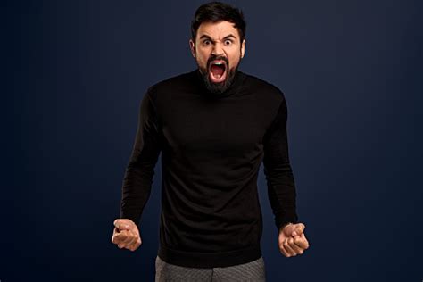 긴장 게임 및 감정 개념 격려 갈색 티셔츠에 흥분 잘 생긴 수염 남자 팀을 응원하기 위해 큰 내기를하고 Tv에서 와서 고함 주먹을 움켜 쥐고 소리 푸른 배경 근육질 남자에