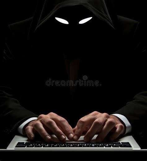 Mysterious Hacker In Dark Hoodie Typing On Laptop Illuminated Eyes