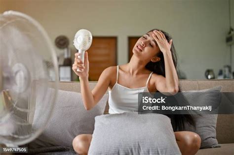 아름다운 아시아 여성이 편리한 선풍기와 선풍기로 자신을 상쾌하게 합니다 선풍기 전기 설비에 대한 스톡 사진 및 기타 이미지 선풍기 전기 설비 바람 불기 Istock