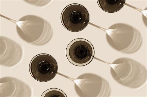 베이지 색 배경에 회색 유리에서 샴페인 안경 창조적 인 기하학적 패턴으로 태양에서 아름다운 그림자와 가성 여름 가벼운 음료 와인 잔 최고 전망 빈티지 유리 제품 그림자에