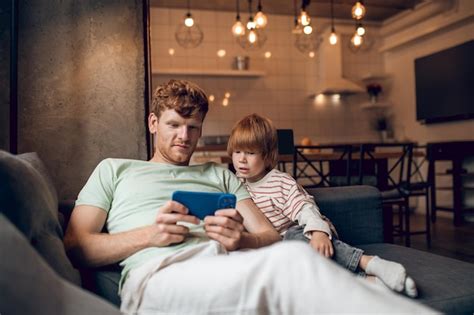 Premium Photo Ginger Father And Son At Home See Together Into The Device