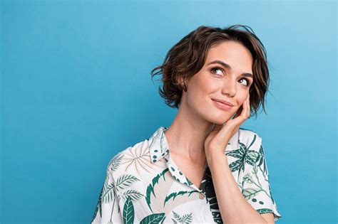 세련 된 헤어 스타일을 입고 인쇄 셔츠를 입는 좋은 긍정적 인 여자의 초상화는 파란색 배경에 고립 된 광대뼈에 빈 공간 팔을 봅니다 25 29세에 대한 스톡 사진 및 기타