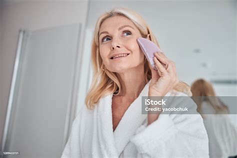 욕실에서 실리콘 기반 브러시와 함께 즐거운 시간을 즐기는 행복한 쾌활한 금발의 여자 45 49세에 대한 스톡 사진 및 기타 이미지 45 49세 개선 건강관리와 의술