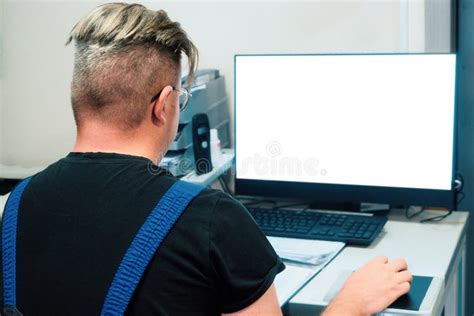 Working Man Sits At Desk And Looks At Computer Monitor View From Back