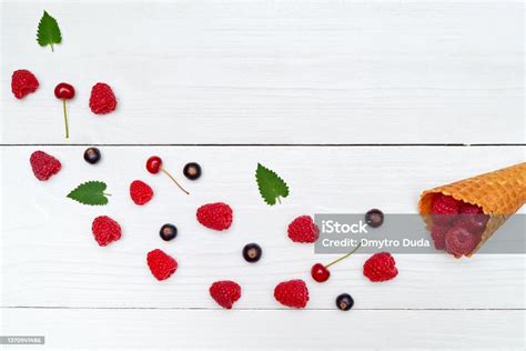 아이스크림 와플 콘에 익은 달콤한 라즈베리 체리와 검은 건포도 복사 공간을 복사합니다 흰 나무 배경에 신선한 열매 여름과 건강한