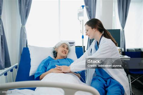 흰 양복을 입은 의사가 상담하면서 메모를 하고 있는 아시아계 고령자 여성 병원이나 진료소에서 식염수를 맞고 침대에 누워 있는