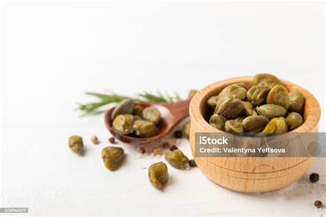 나무 부엌 테이블에 케이퍼 바다 소금과 로즈마리를 곁들인 케이퍼 절인 케이퍼 지중해 요리 재료 유기농 향신료와 조미료 공간을 복사합니다 건강한 생활방식에 대한 스톡 사진 및