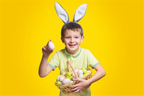 부활절 토끼 귀를 쓰고 행복한 스밀링 소년이 노란 배경에 그려진 달걀바구니를 들고 있다 공간을 복사합니다 부활절 날 바구니에 대한 스톡 사진 및 기타 이미지 Istock