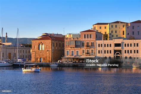 낚시 보트는 올드 베네치아 항구 하니아 크레타 그리스의 그랜드 아스날을 통과합니다 부두와 부두 카페에 정박한 범선의 일출 전망 0명에 대한 스톡 사진 및 기타 이미지