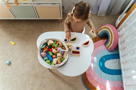 놀이방의 테이블에 나무 블록을 가지고 노는 어린 소녀 현대 보육원에서 아기와 유아를위한 교육 게임 아이는 나무 무지개 쌓기