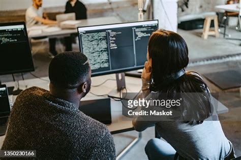 Male And Female Programmers Coding Over Computer In Creative Office