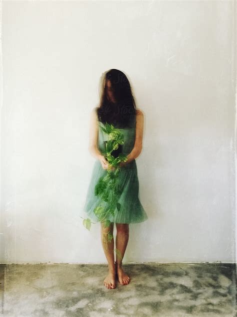 Movement Shot Of Unrecognisable Female Wearing Green Dress Holding Devils Ivy Plant By