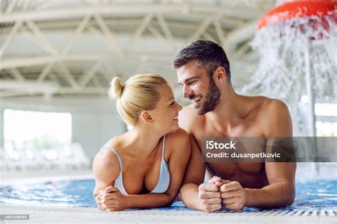 온천과 미네랄 워터가 있는 수영장에 서서 눈을 바라보며 서로를 바라보는 사랑스러운 부부 스파 및 웰니스 센터에서 로맨틱한 순간을 만드실 수 있습니다 스파에서 커플 2명에