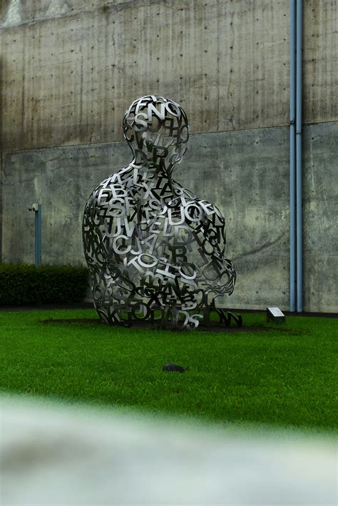 A Sculpture Of A Person Sitting In The Grass Photo Free Grass Image