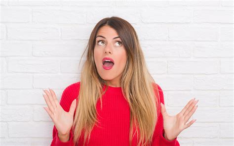 집에서 하 고 외치는 적극적인 식와 팔 제기 함 화 겨울 옷을 입고 흰 벽돌 벽을 통해 젊은 성인 여자 좌절 개념입니다 가을에