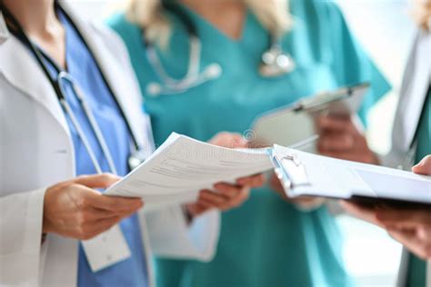 Staff Meeting Between Doctors And Nurses Sharing Patient Documents In