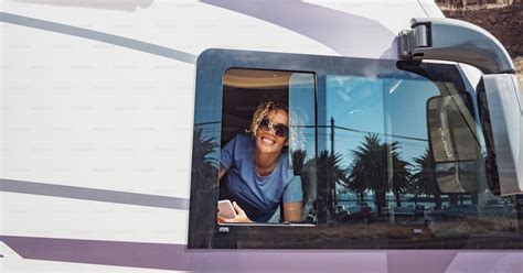 그녀의 현대 캠핑카 밴 모터 홈의 창문에서 웃고 있는 행복한 여자 초상화 휴가 휴가 또는 밴 생활 라이프 스타일을위한 관광 및 여행의 개념 목적지에서 행복한 젊은
