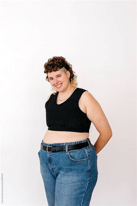 happy plump non binary person with hands behind back by stocksy