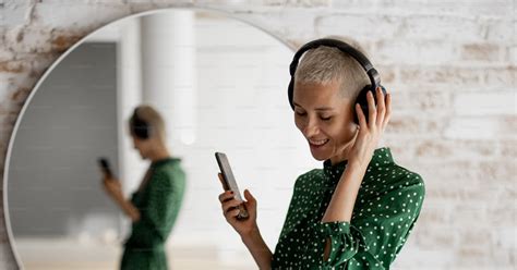 녹색 드레스를 입은 세련된 여자는 집에서 거실에서 헤드폰과 휴대폰 춤으로 음악을 즐긴다 사진 Unsplash의 여자 이미지