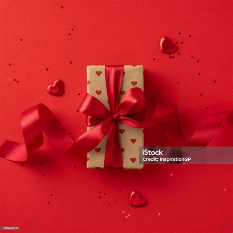 사랑과 축하를 상징하는 빨간 배경에 빨간 리본과 하트 장식이 있는 아름답게 포장된 선물 상자의 정사각형 사진 발렌타인 데이와 로맨틱한 행사에 적합합니다 0명에 대한 스톡